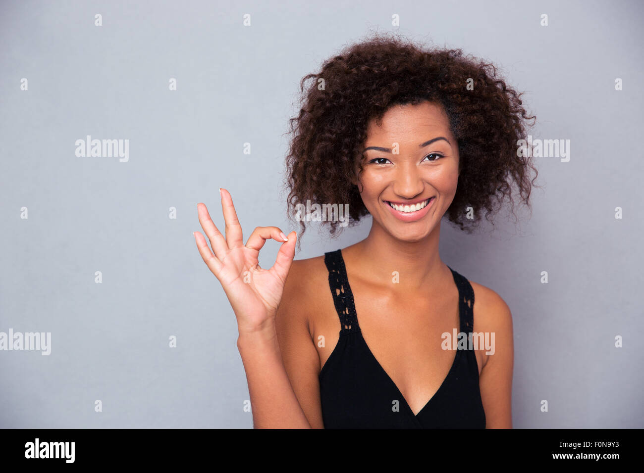 Portrait of a smiling black woman showing ok sign with fingers over ...