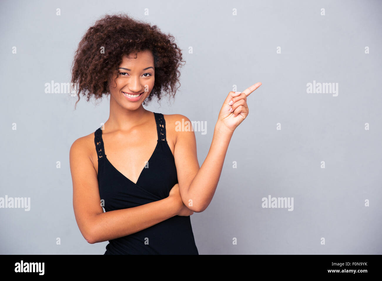 Portrait of a happy african man pointing finger away over gray ...