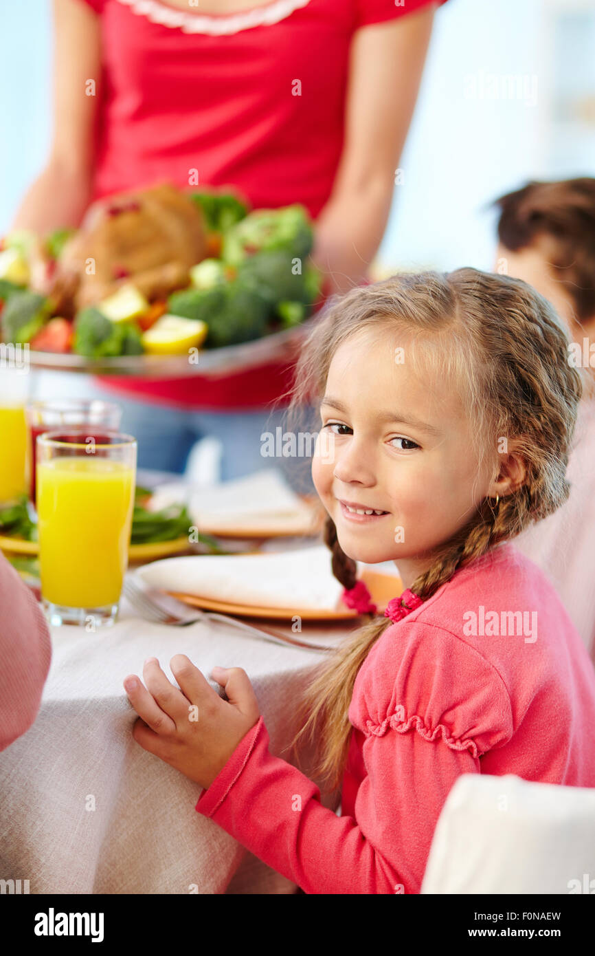 Little girl sitting at dining table with her family Stock Photo - Alamy