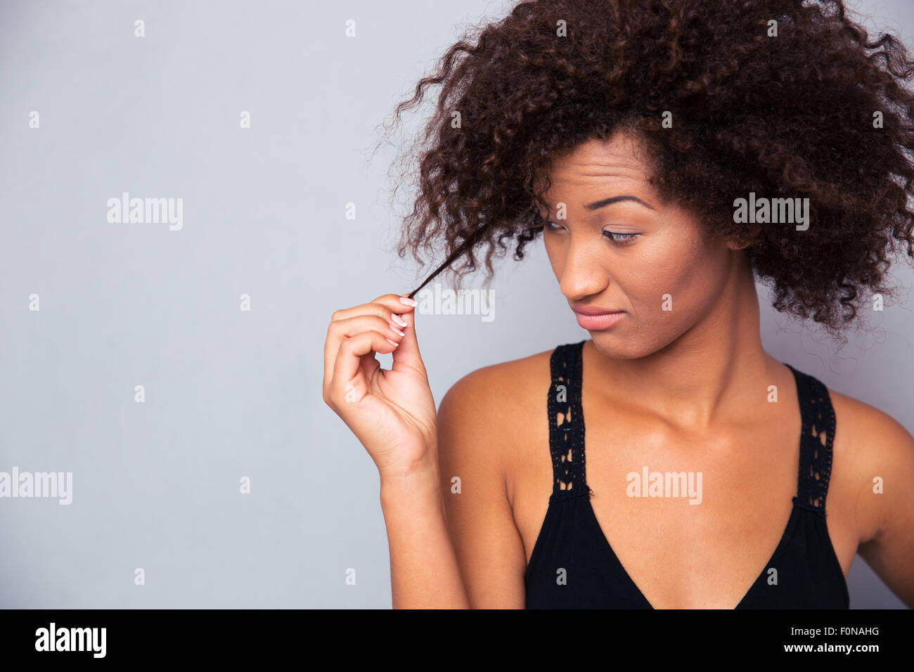 Portrait of a young afro american woman touching her hair over gray ...