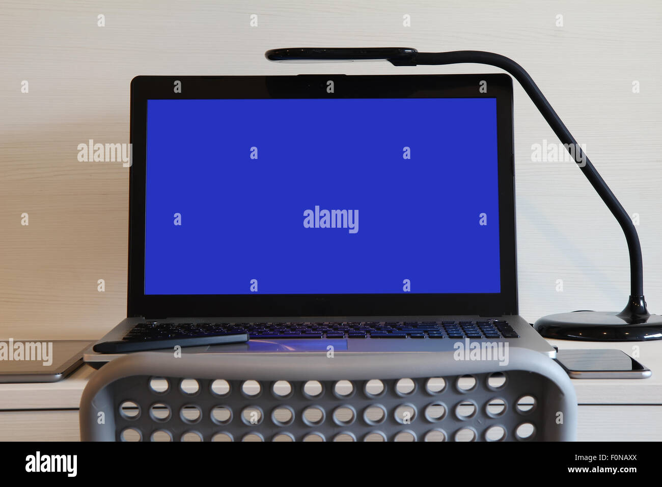 blank blue screen laptop computer with table lamp is on twooden desk as ...