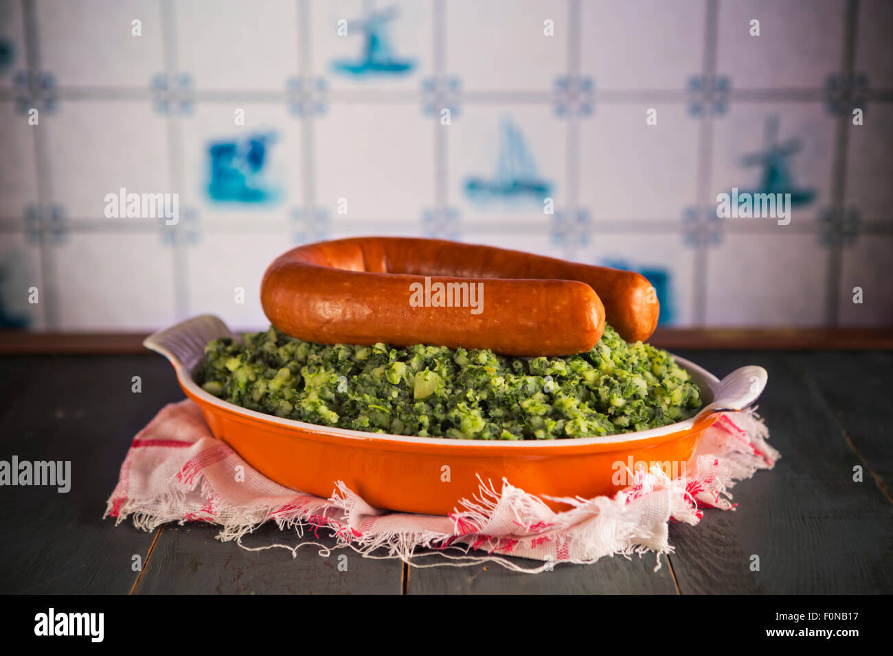 A rustic kitchen with a dish with 'Boerenkool met worst' or kale with ...