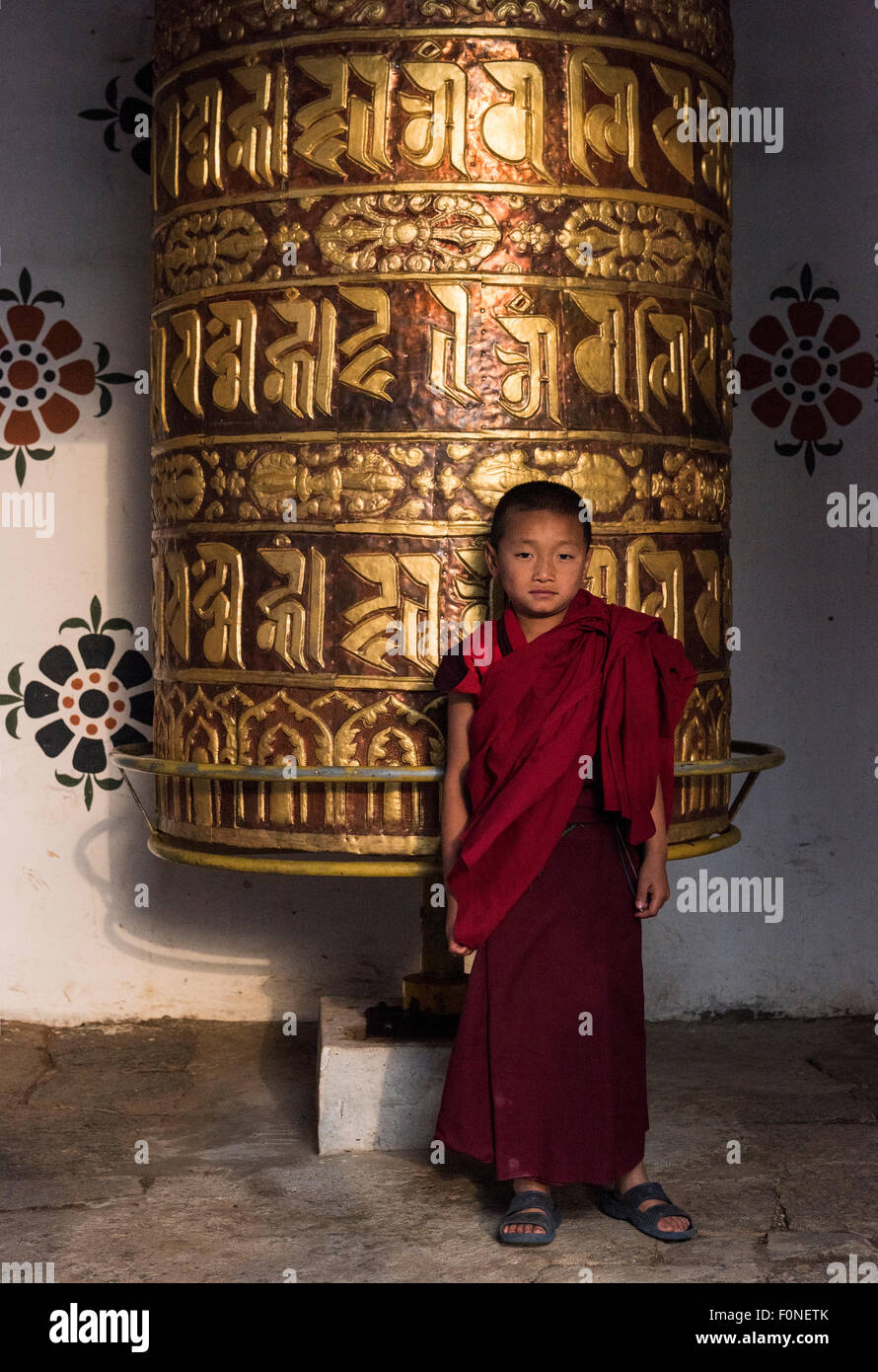 Young Buddhist monk by a prayer wheel at Chime (or Chimmi) Lhakhang or ...