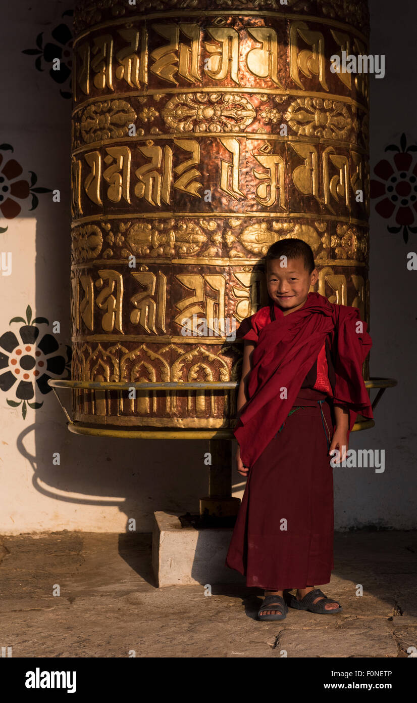 Young Buddhist monk smiling by a prayer wheel at Chime (or Chimmi ...