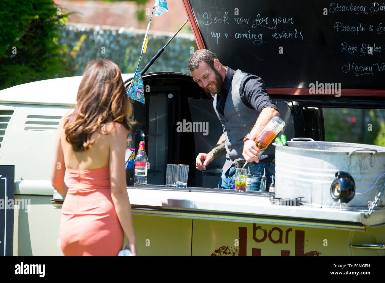 A man serving a drink from a cocktail bar made out of a vw camper van ...