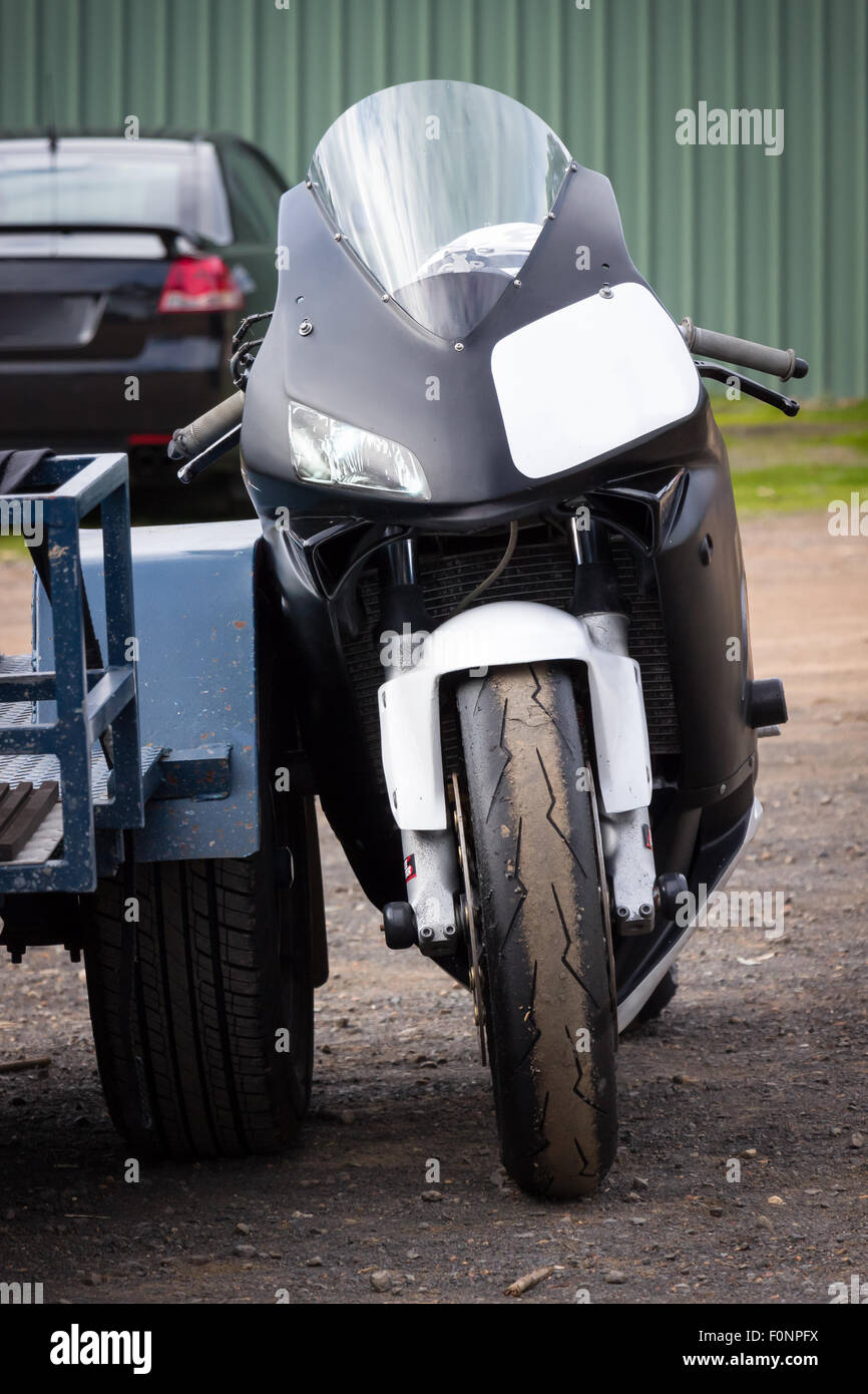 A modern racing superbike leaning against its trailer in the paddock at ...