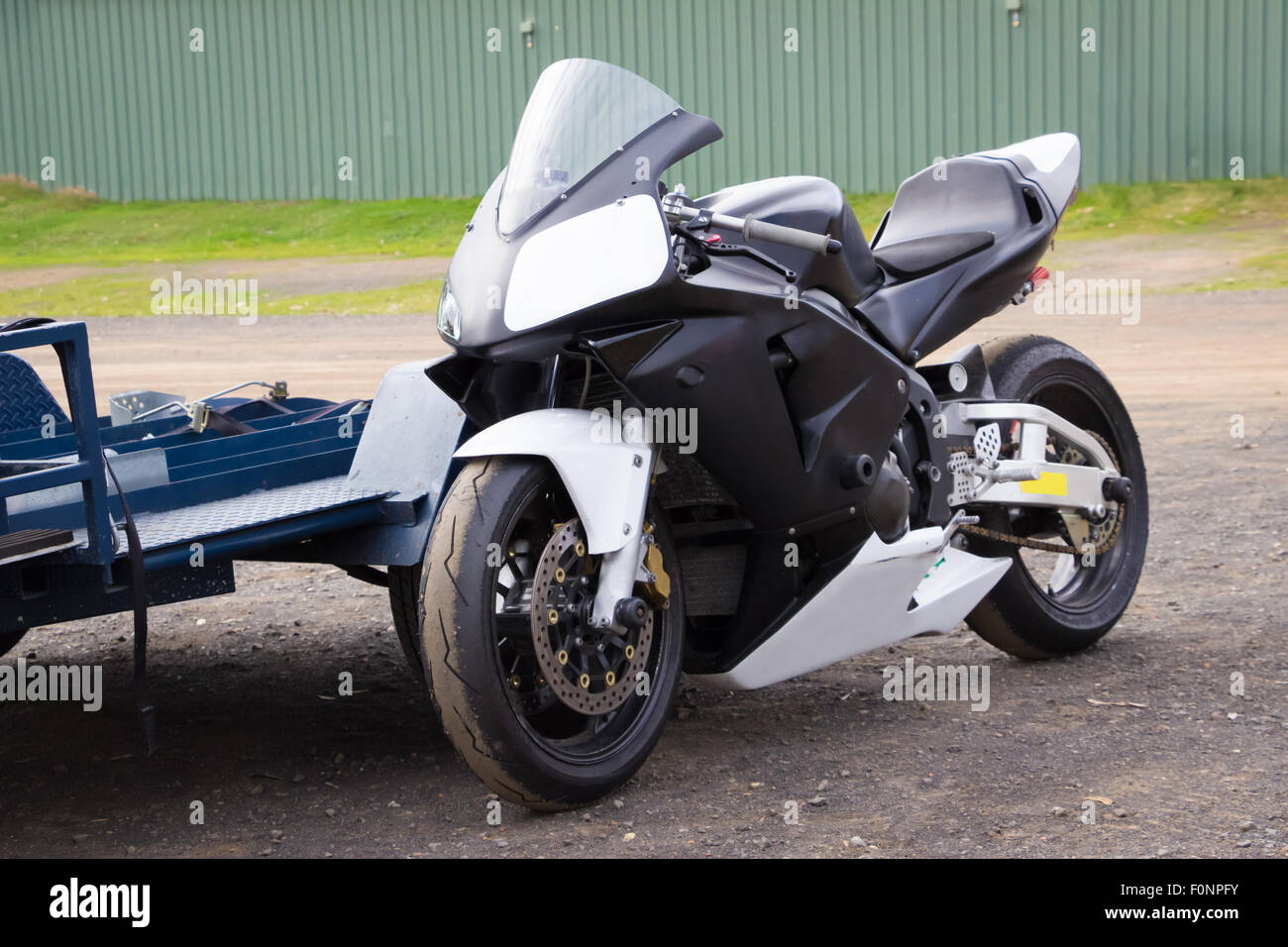 A modern racing superbike leaning against its trailer in the paddock at ...