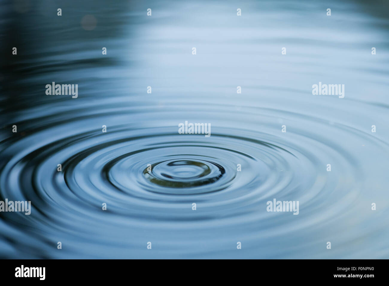 Droplet falling in blue water Stock Photo - Alamy