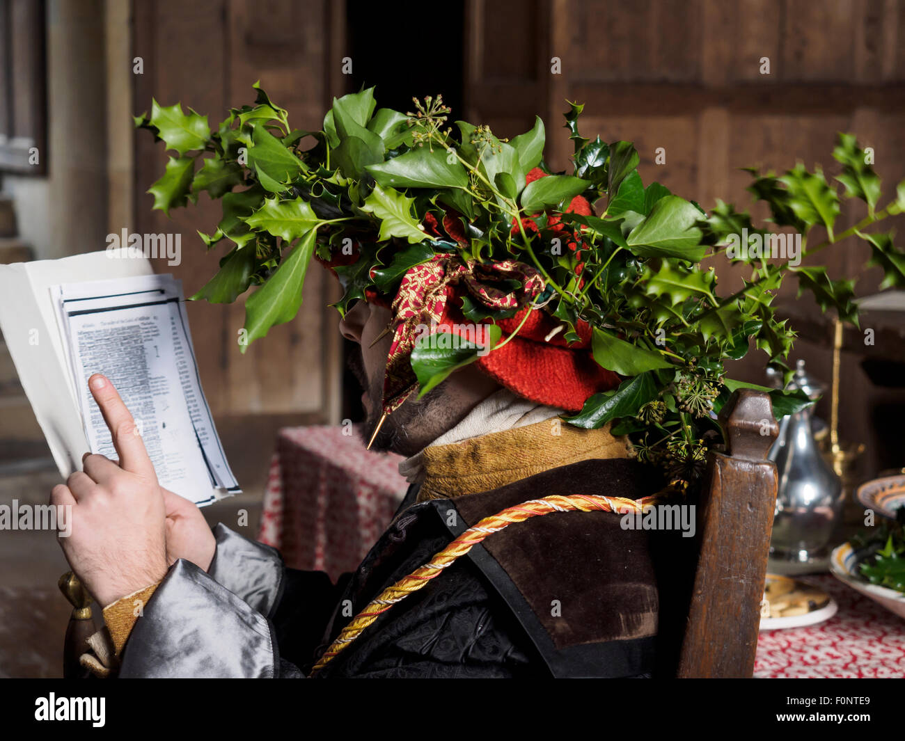 Man wearing holly crown reading book during Tudor Christmas in Haddon ...