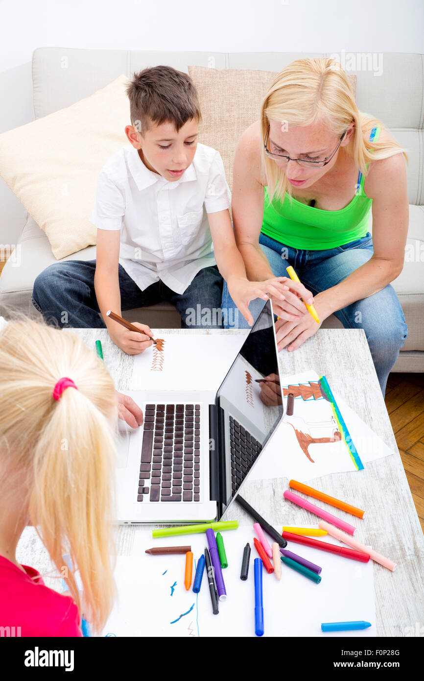 Kids drawing with happy parents on the couch Stock Photo - Alamy