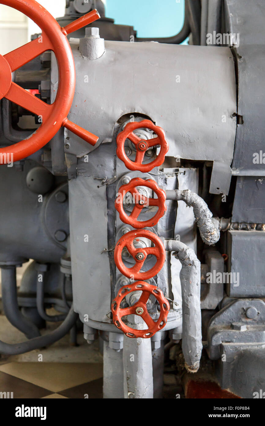 Close up detailed view of red round valves, with grey mechanical tools ...