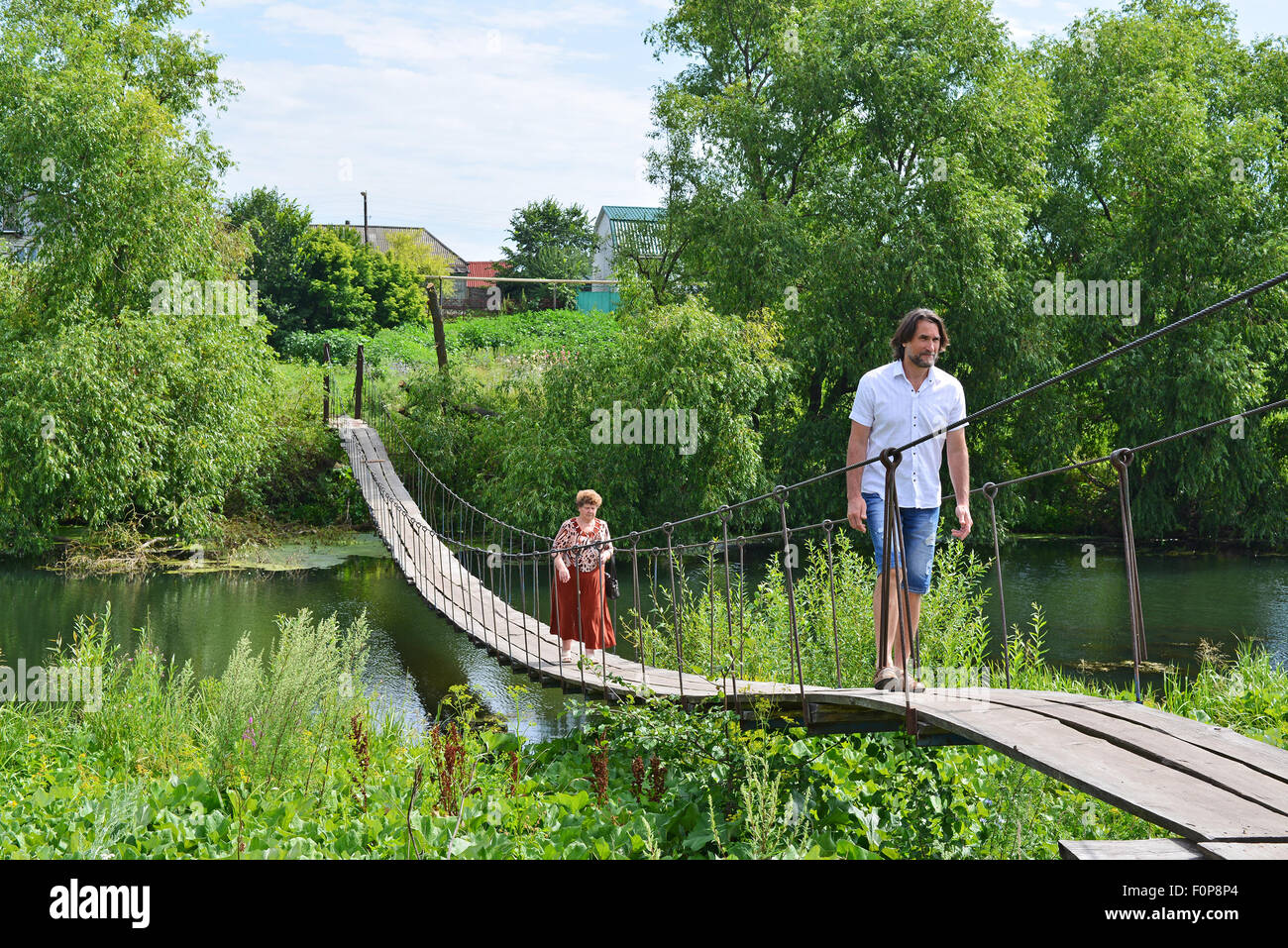 two people go on a suspension bridge over the river Stock Photo - Alamy