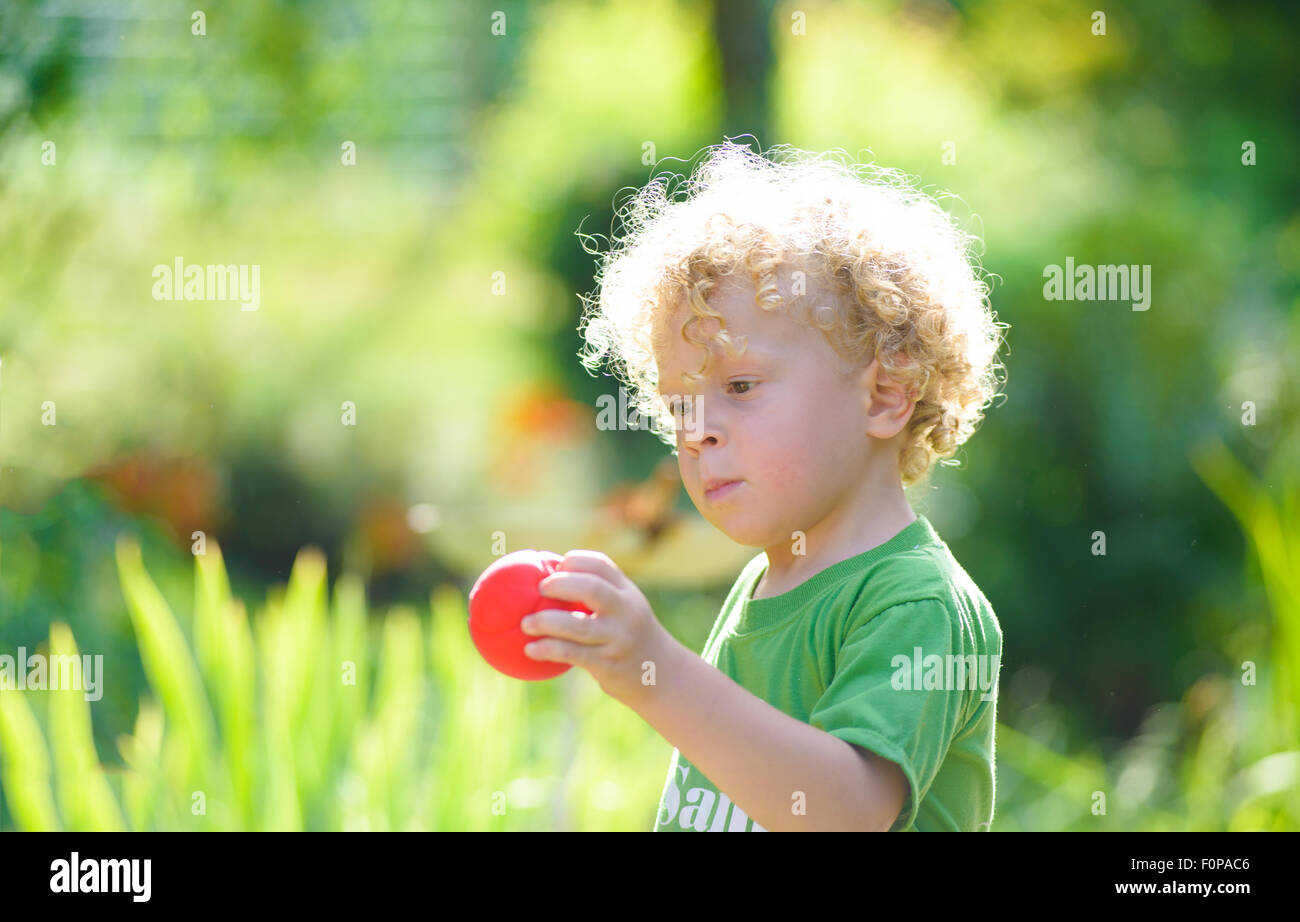 a blond child with a small red ball Stock Photo - Alamy