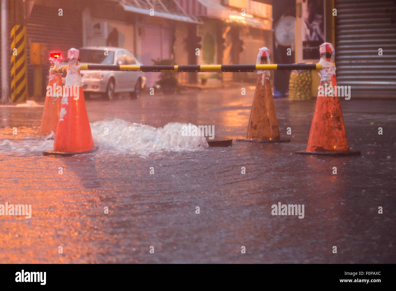 Orange cones around overflowing manhole during typhoon Stock Photo - Alamy