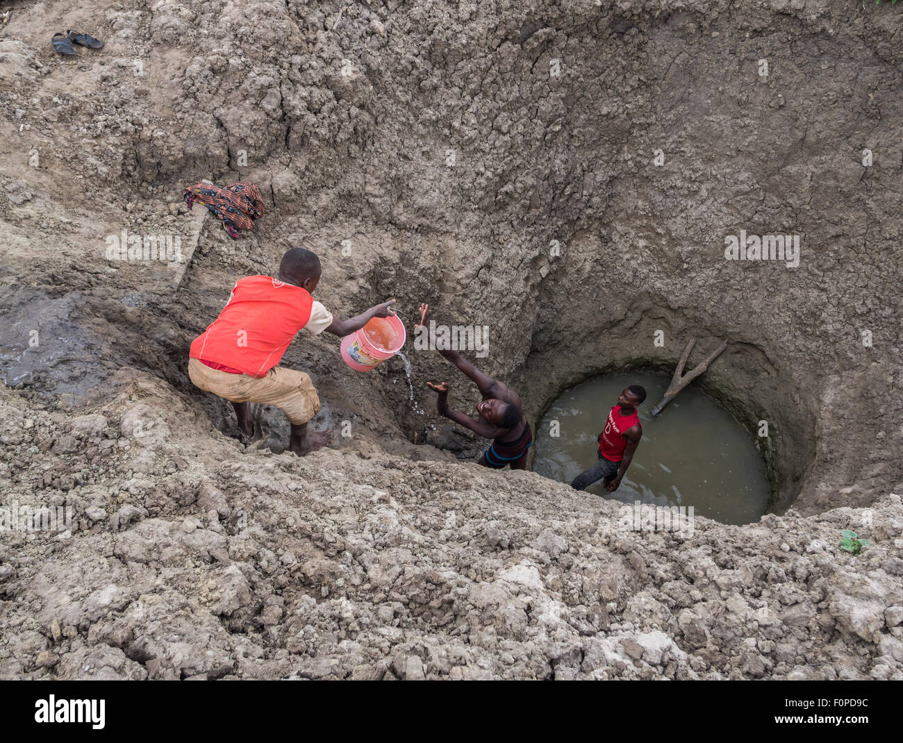 Men getting water for their cattle from a deep artificial hole in ...