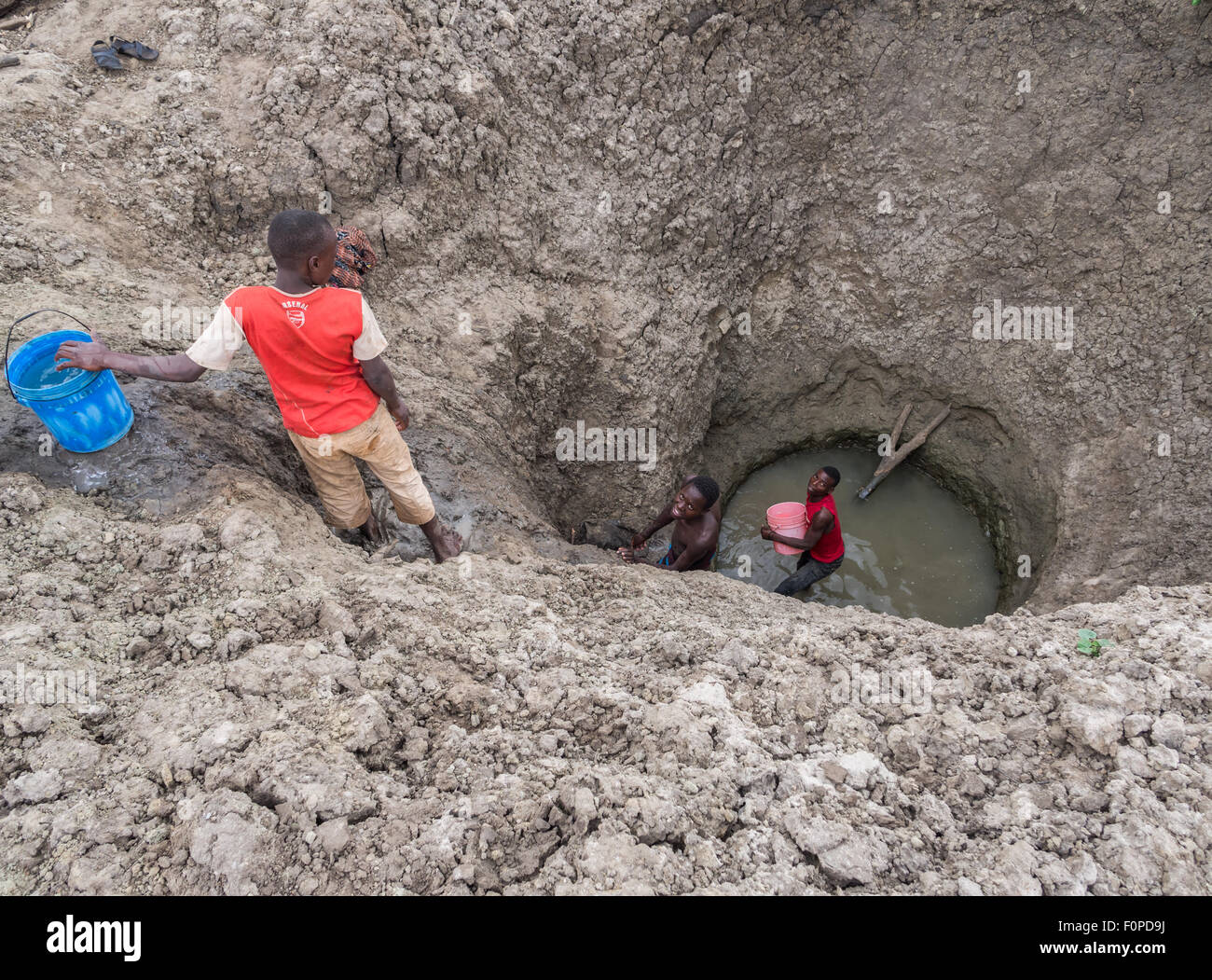 Men getting water for their cattle from a deep artificial hole in ...