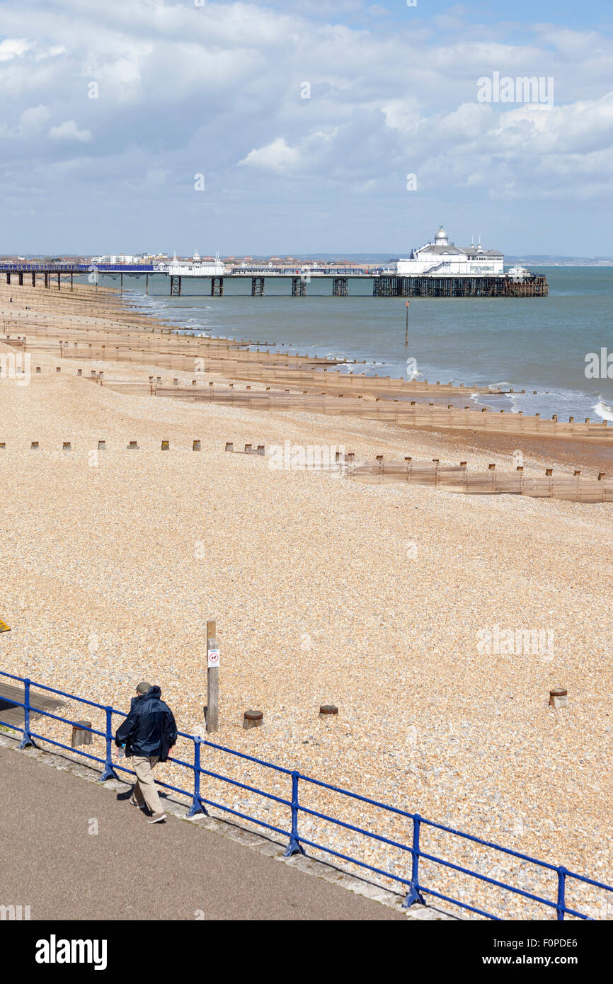 The pier and beach, and a man walking along the promenade, Eastbourne ...
