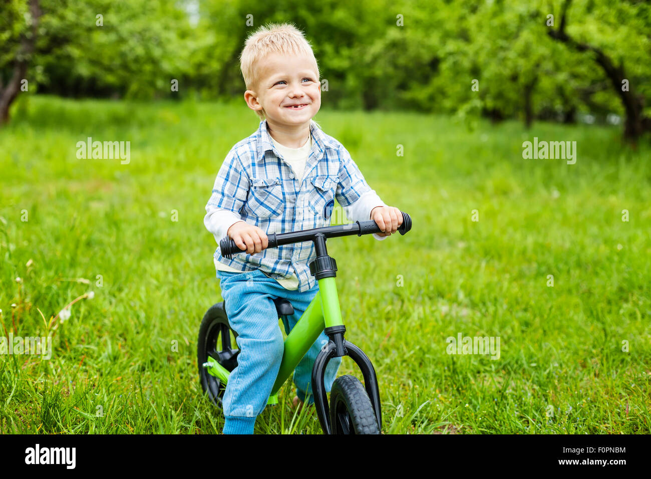 Happy little boy riding learner bike on grass Stock Photo - Alamy