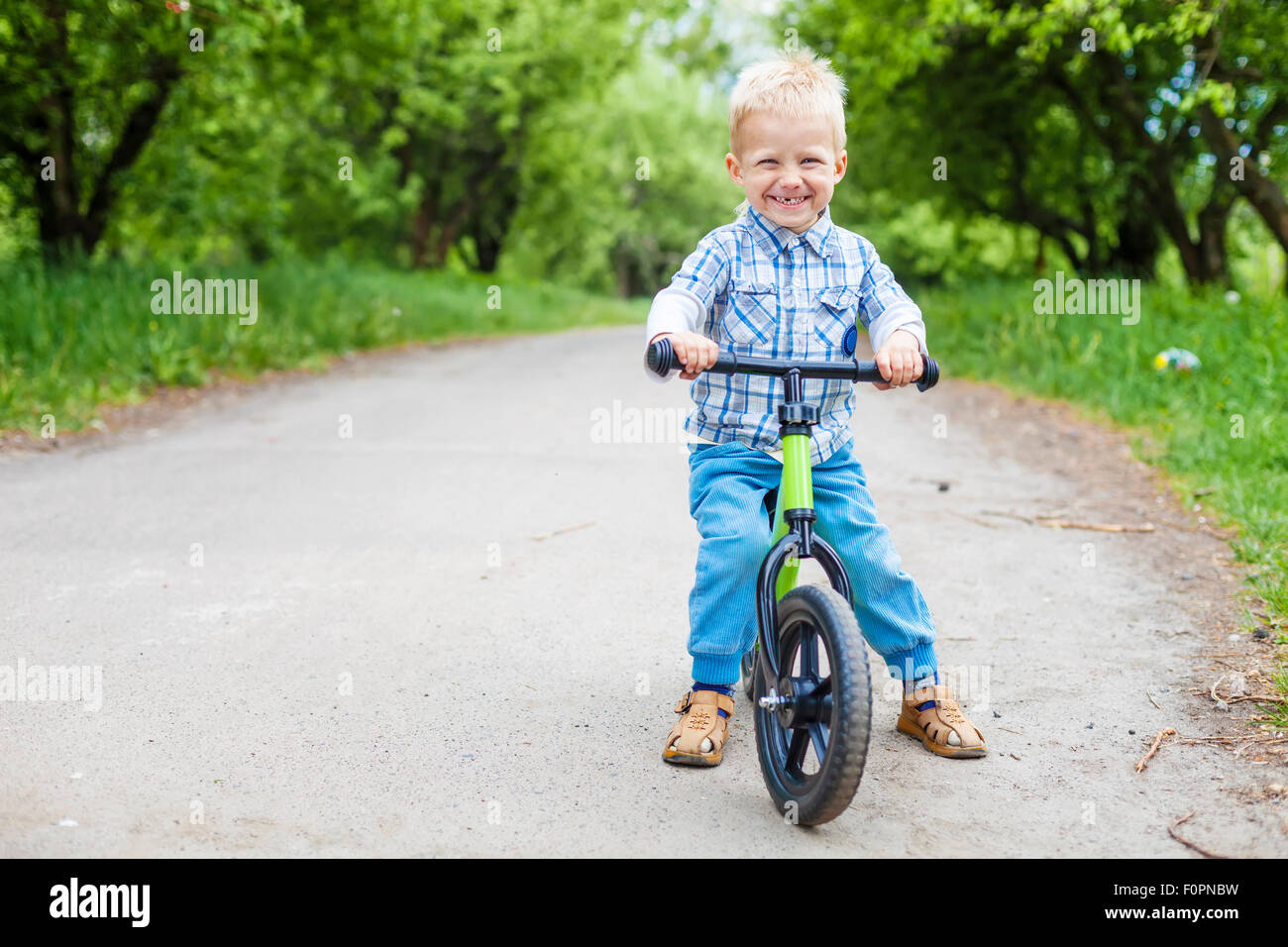 Happy little boy riding learner bike Stock Photo - Alamy