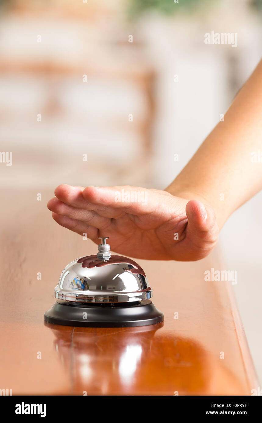 hand ringing hotel bell in reception desk close up selective focus ...