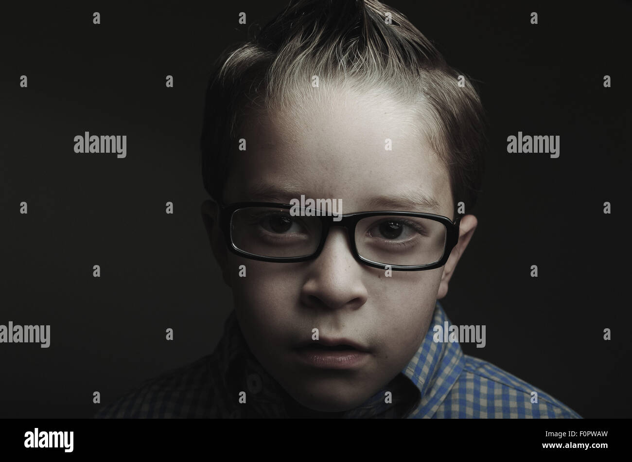 Low key closeup portrait of little boy looking sad Stock Photo - Alamy