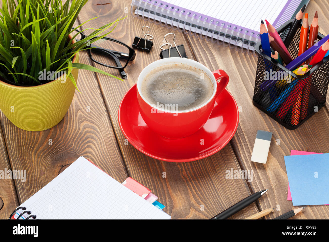 Office table with flower, supplies and coffee cup. View from above ...