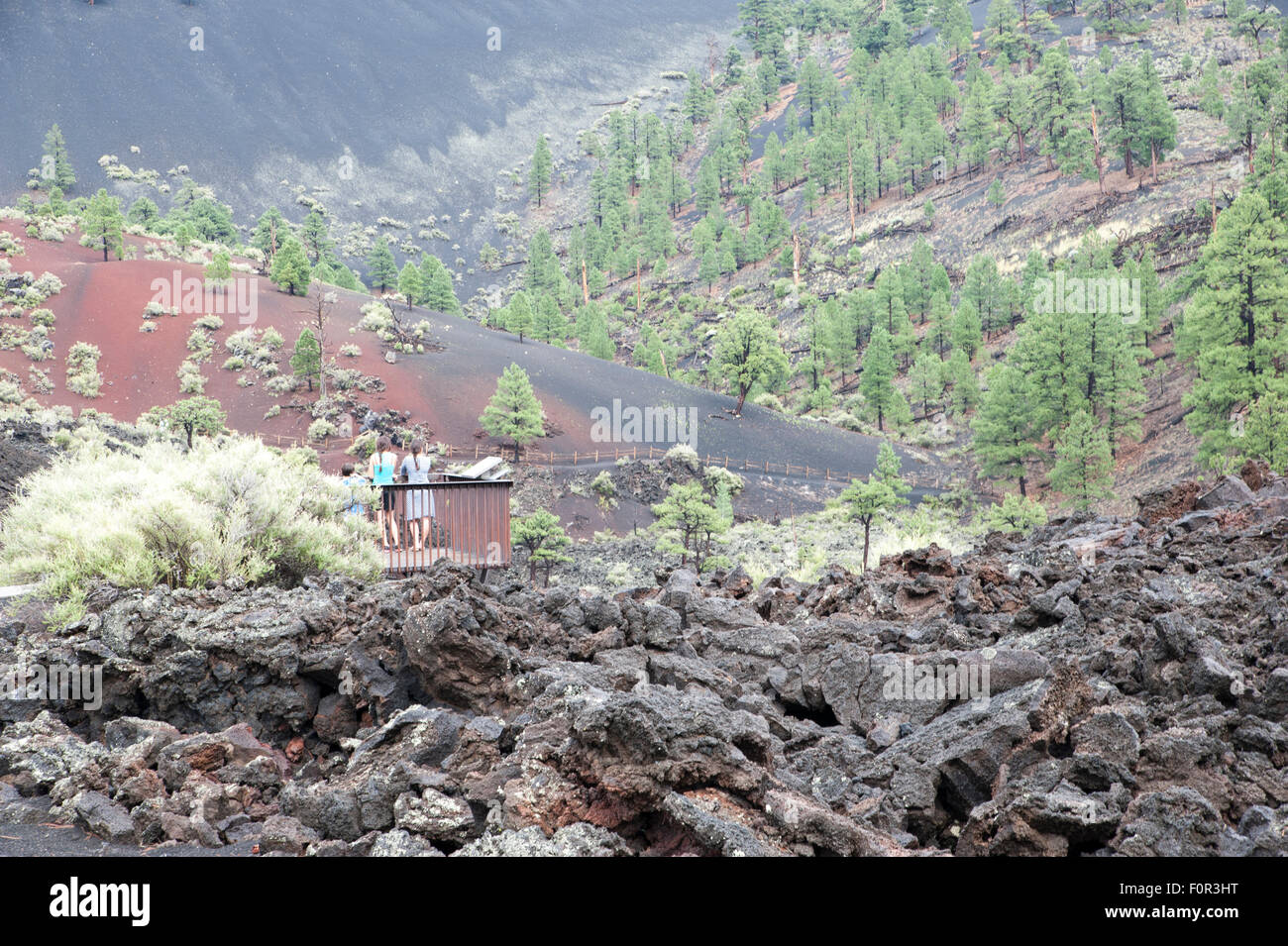 Tourists look from a vista at Sunset Crater Volcano National Monument ...