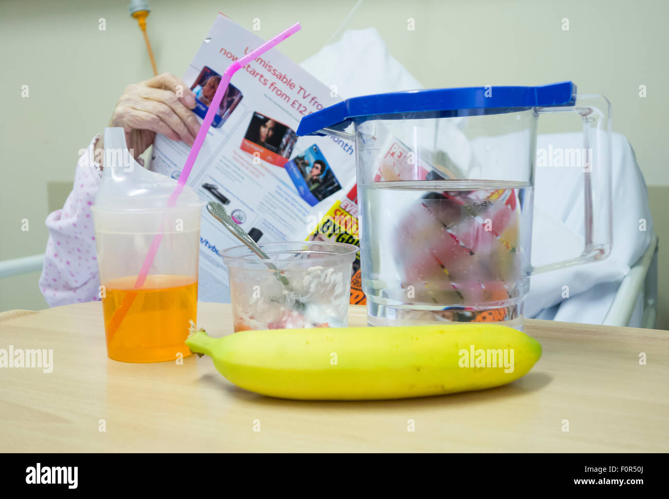 Ninety year old lady in NHS hospital bed with jug of water, juice drink ...