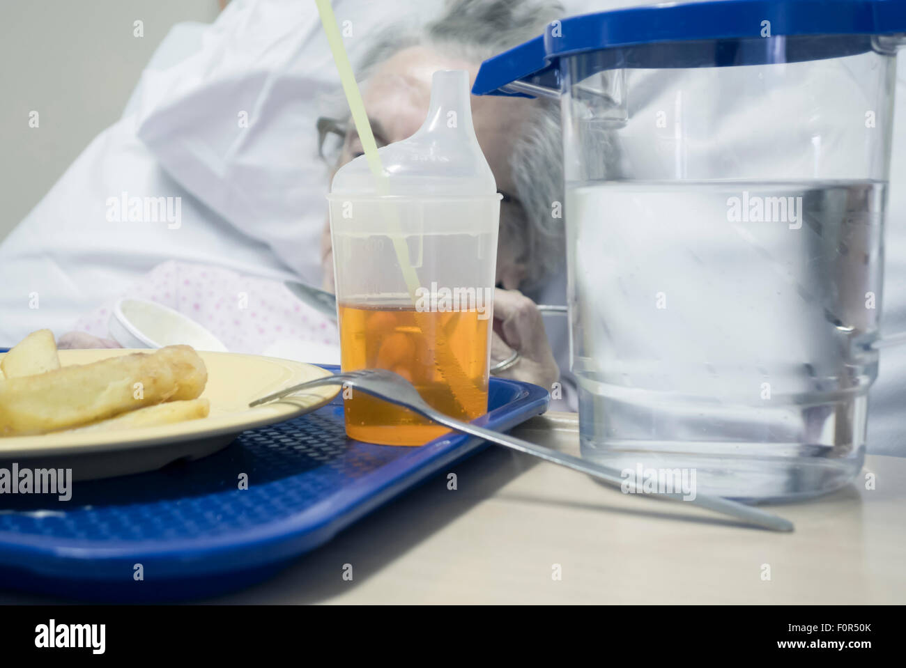 Hospital food. Ninety year old lady in NHS hospital bed with jug of ...