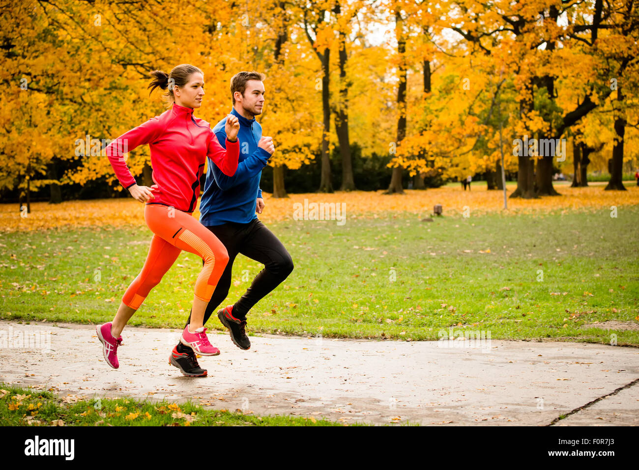 Young couple jogging together in park - rear view Stock Photo - Alamy