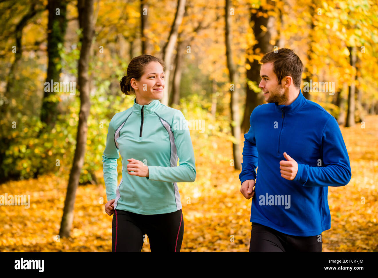 Young couple talking while jogging together in beautiful autumn nature ...