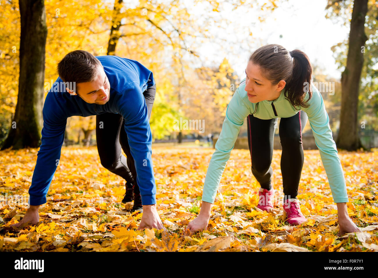 Young couple in steady position prepared for running in autumn nature ...