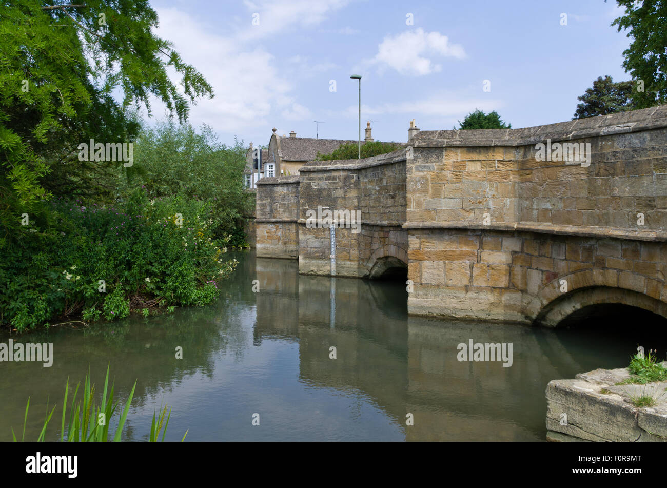 The fine three arched Medieval bridge over the River Windrush at the ...