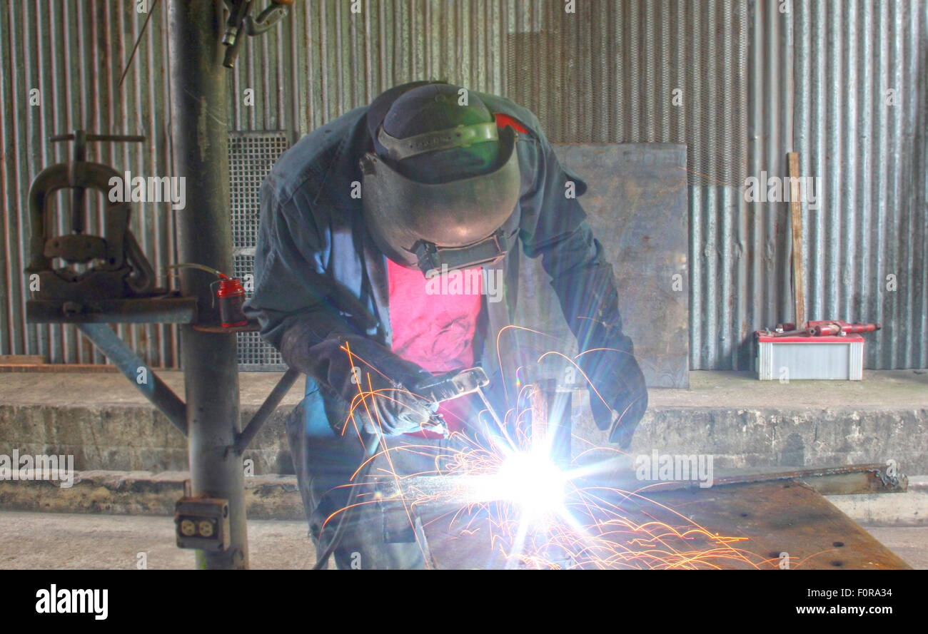 Man welding a piece of iron on a work table in a shop Stock Photo - Alamy
