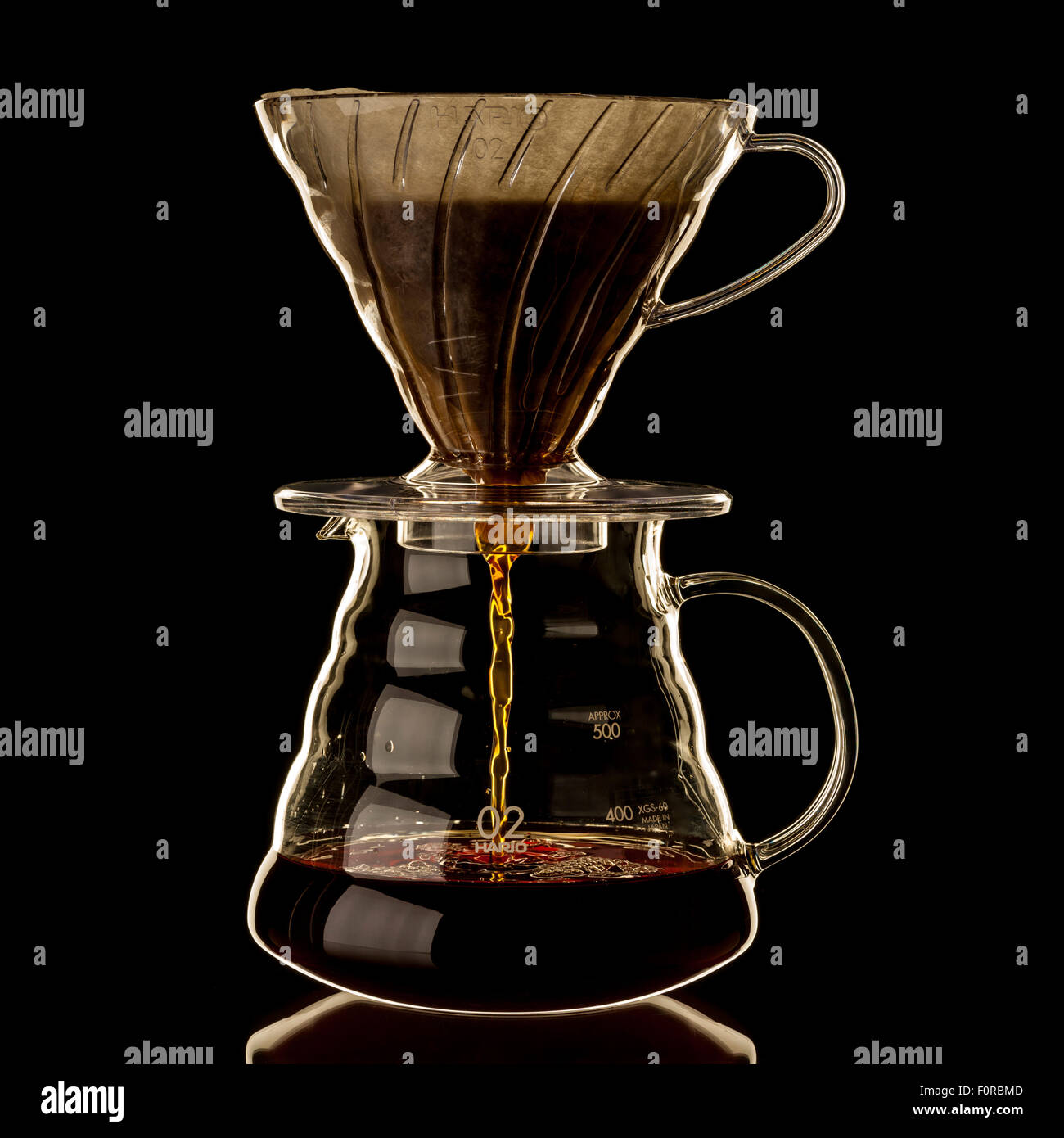 Coffee filtering through cone line with filter paper into a glass jug ...