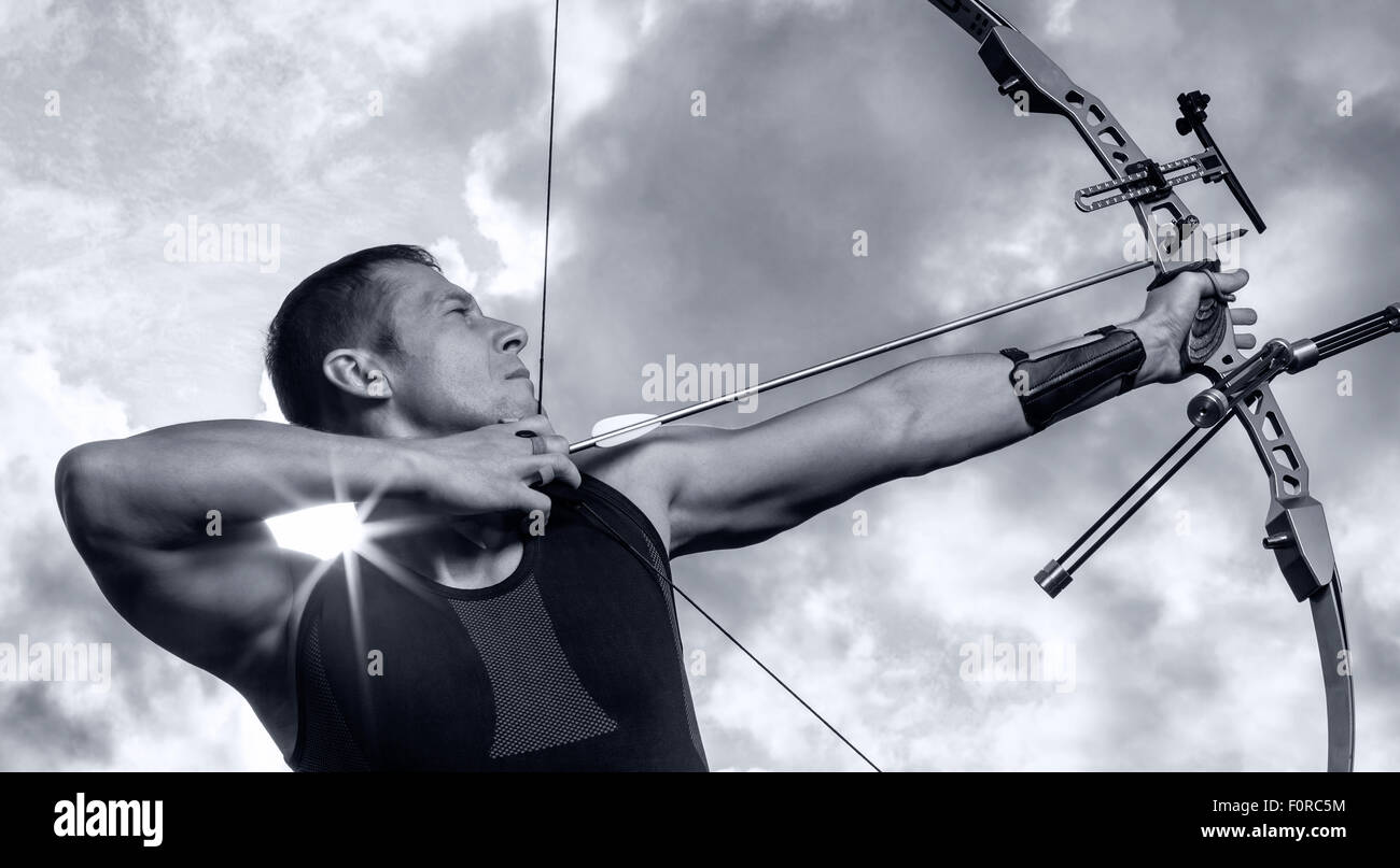 Tough man with bow and arrows, close up with cloudy sky at background ...