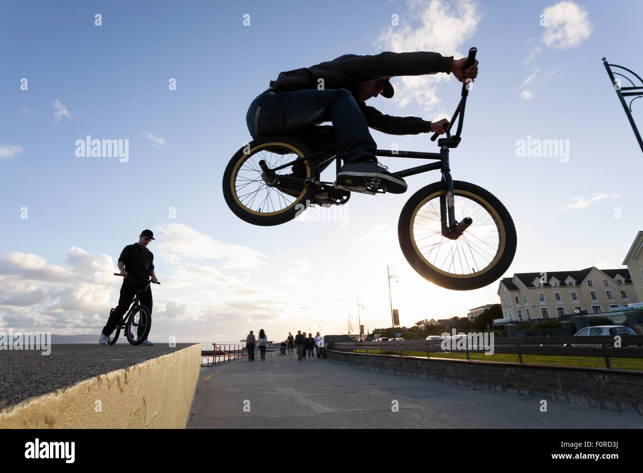Two Young men performs BMX stunts during sunset at the street Stock ...