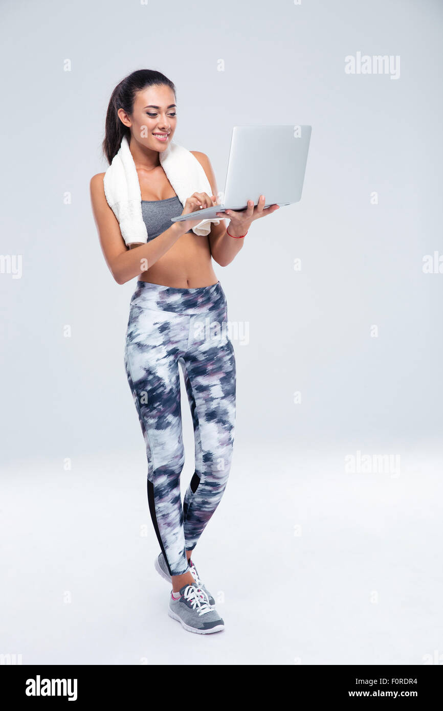 Full length portrait of a happy fitness woman using laptop isolated on ...