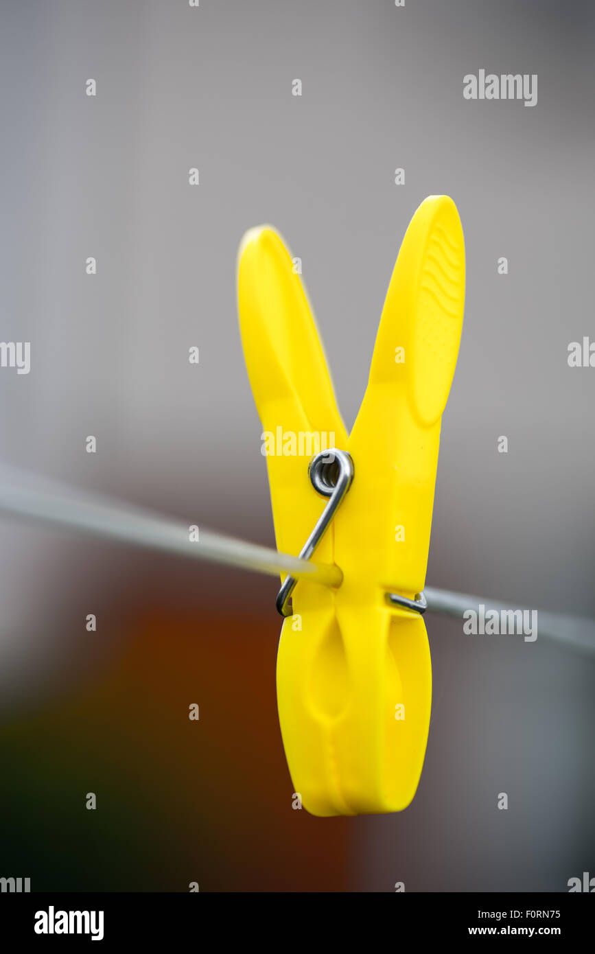 A bright yellow clothes peg hanging on a line Stock Photo - Alamy