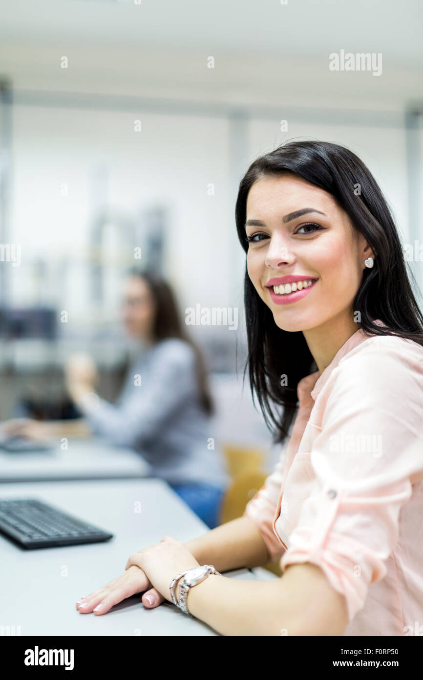 Young beautiful woman smiling happily in a classroom equipped with ...