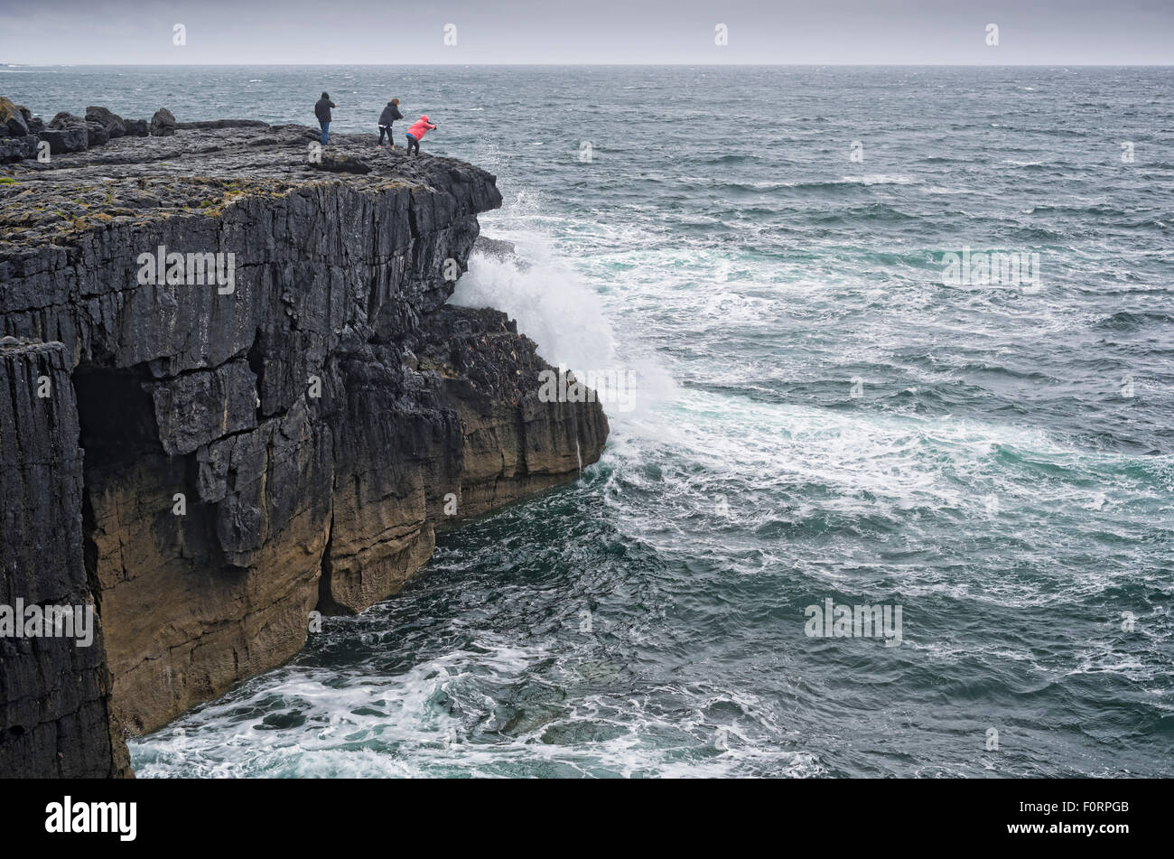 People taking photos of waves hitting cliffs at The burren, Co. Clare ...