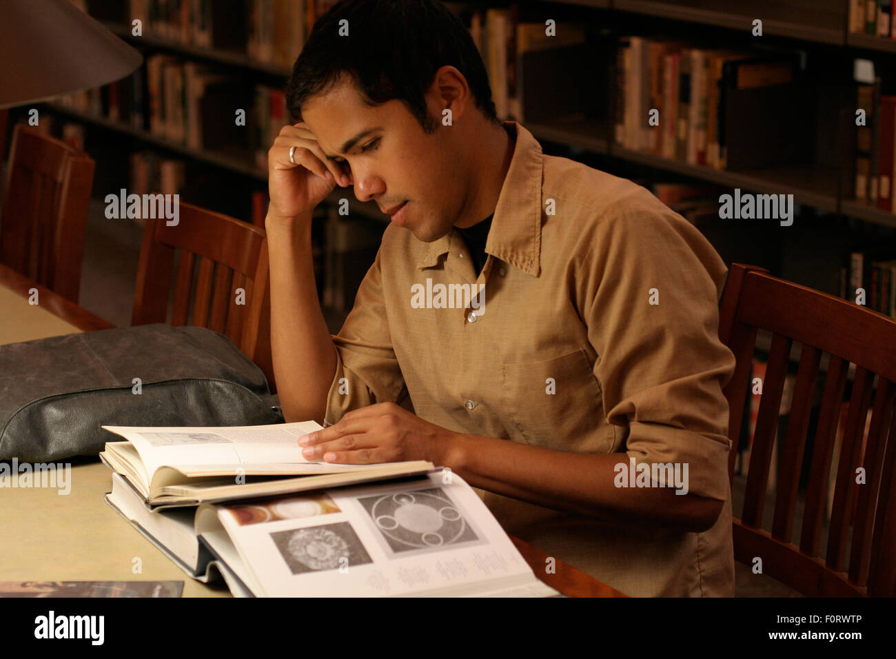College student reading book with head resting on hand Stock Photo - Alamy