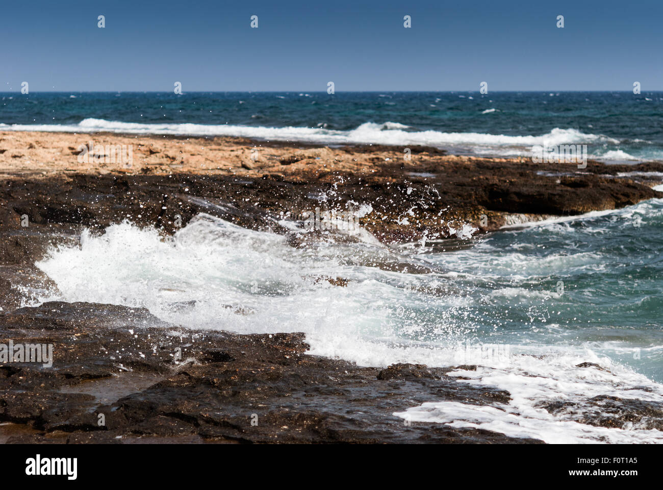 Blue sea waves crashing on a rocky shore Stock Photo - Alamy