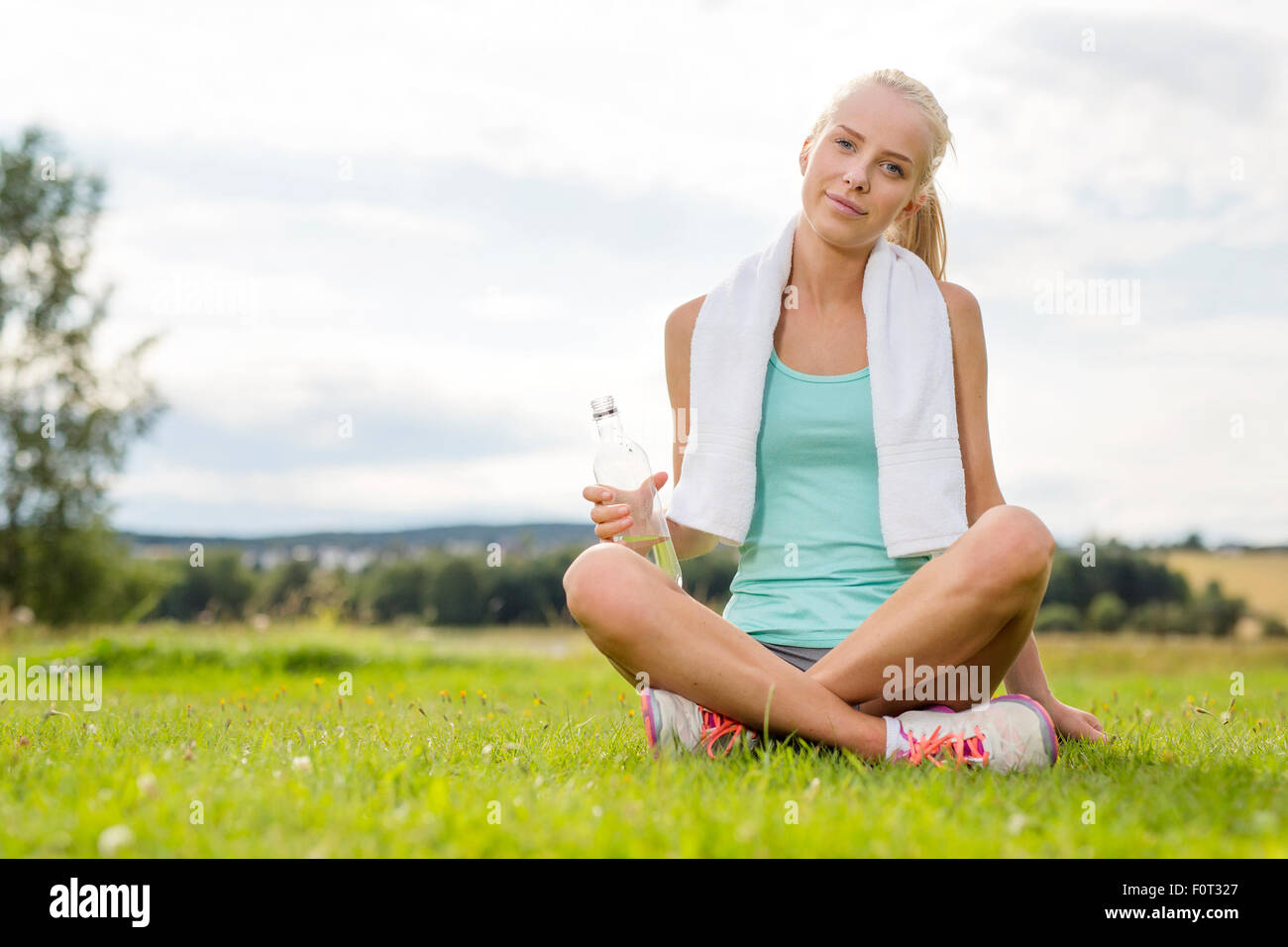 Smiling young woman taking break on the grass Stock Photo - Alamy
