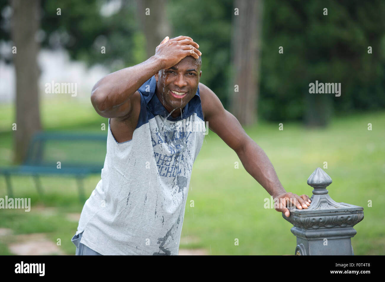 Young man splashing water on face from fountain Stock Photo - Alamy
