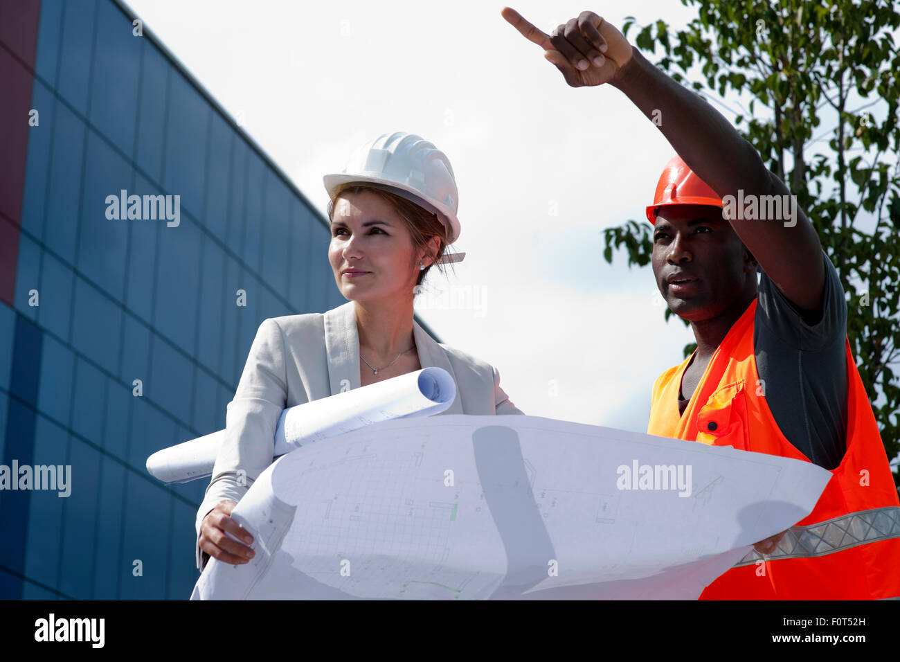 Young female engineer discussing a building project with a construction ...