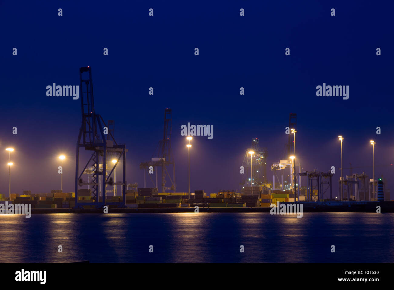 container port pier visible over water, night time Stock Photo - Alamy