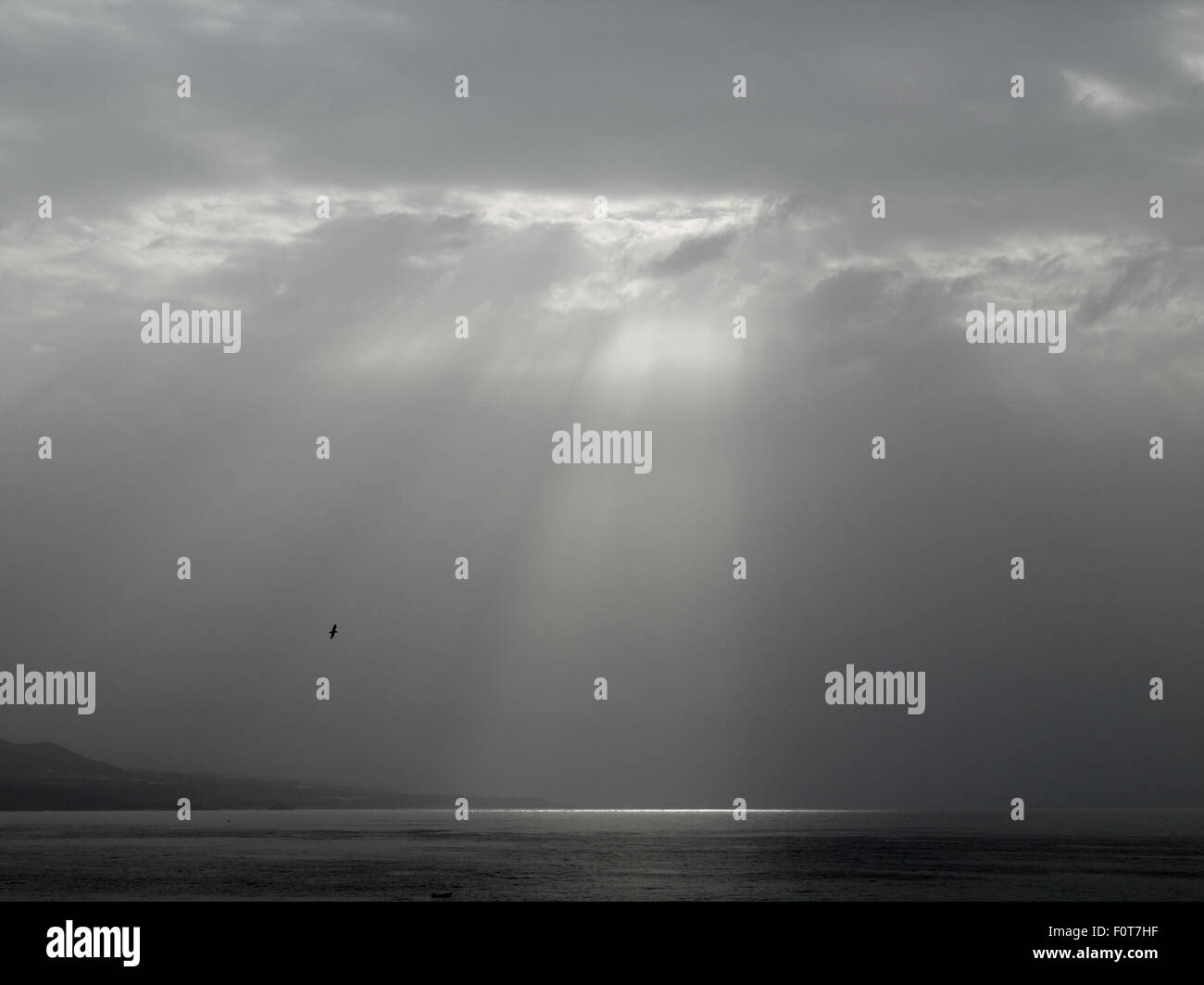 cloudy sky with a single gap in the clouds through which sun rays come ...