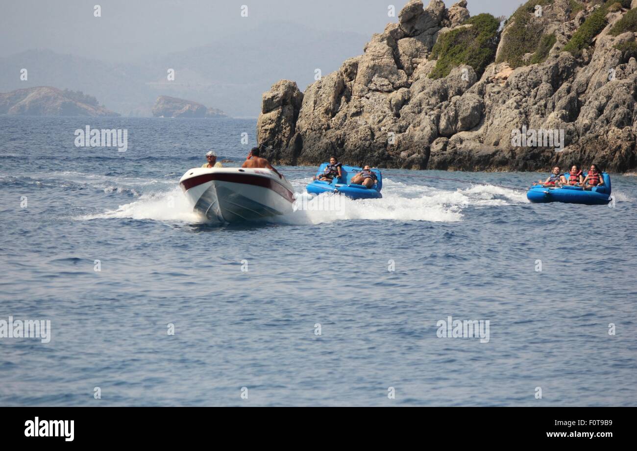 Tourists having fun riding in inflatables being pulled by a speedboat ...