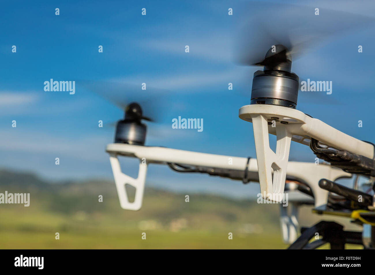 blurred spinning propellers of a hexacopter drone flying over rolling ...